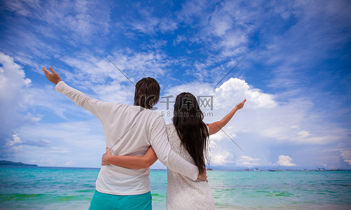 站在白色沙滩上的年轻夫妇张开双臂的背影高清摄影大图-千库网