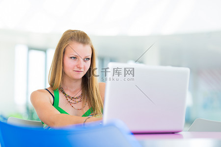 在她的笔记本电脑上工作的漂亮女大学生高清摄影大图-千库网