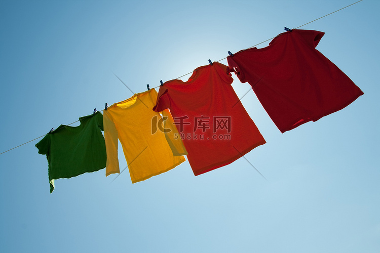 晾衣绳上五颜六色的衣服背后的阳光高清摄影大图-千库网