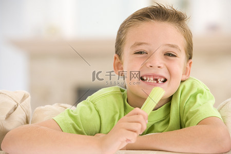 小男孩在客厅里微笑着吃芹菜高清摄影大图-千库网