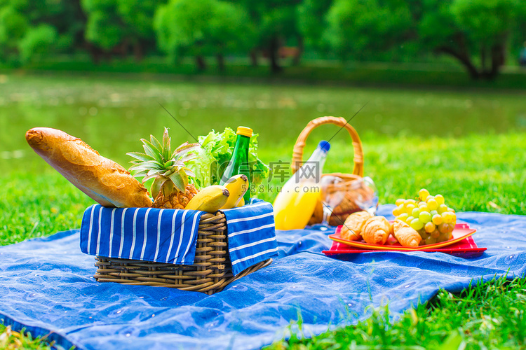 带水果、面包和一瓶白葡萄酒的野餐篮高清摄影大图-千库网