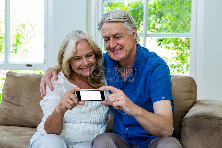 老年夫妇坐在家里使用手机高清摄影大图-千库网