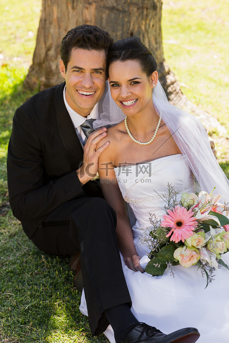 新婚夫妇坐在公园的树干上高清摄影大图-千库网