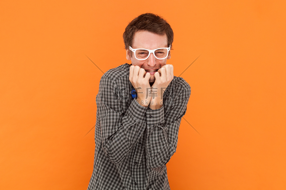 焦虑困惑的男人书呆子咬指甲站立不安全和紧张，感觉不舒服。高清摄影大图-千库网