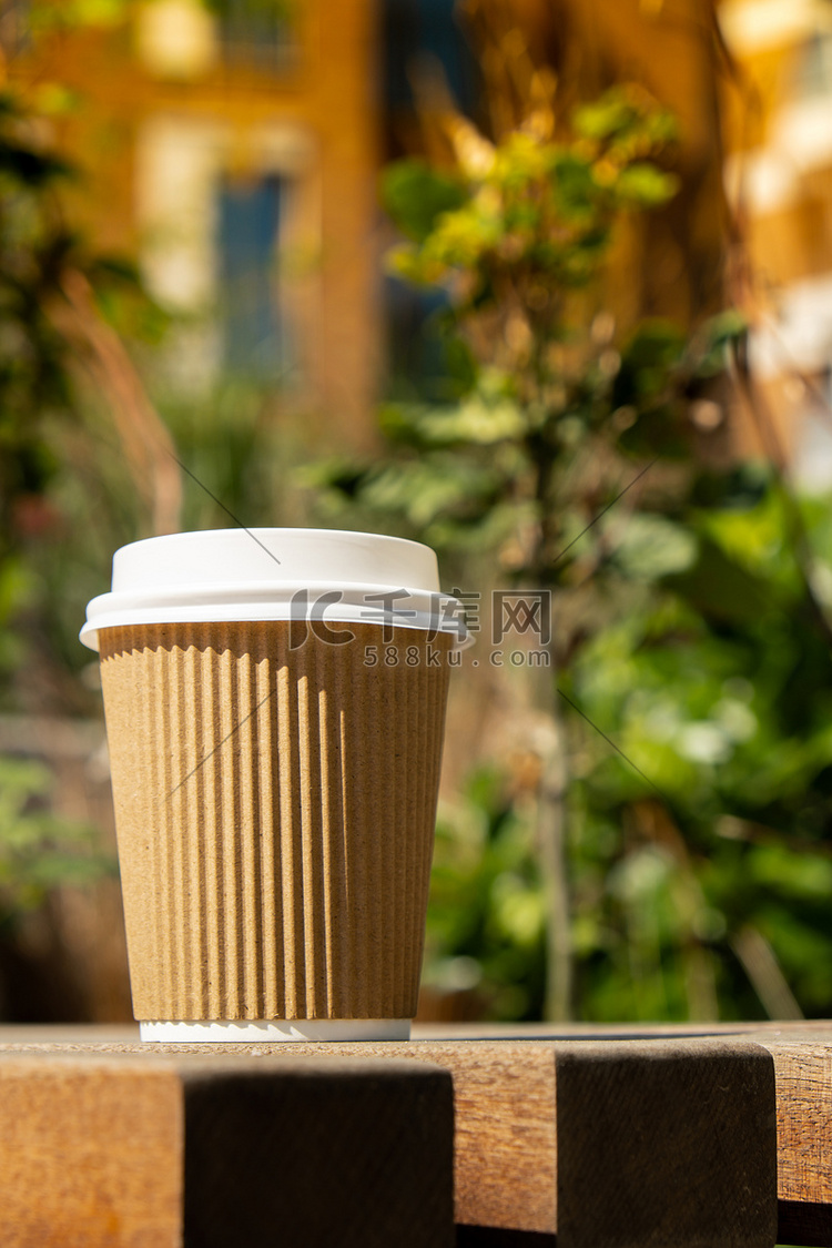 木制桌子上的牛皮纸上有咖啡或茶的生态回收纸杯。高清摄影大图-千库网