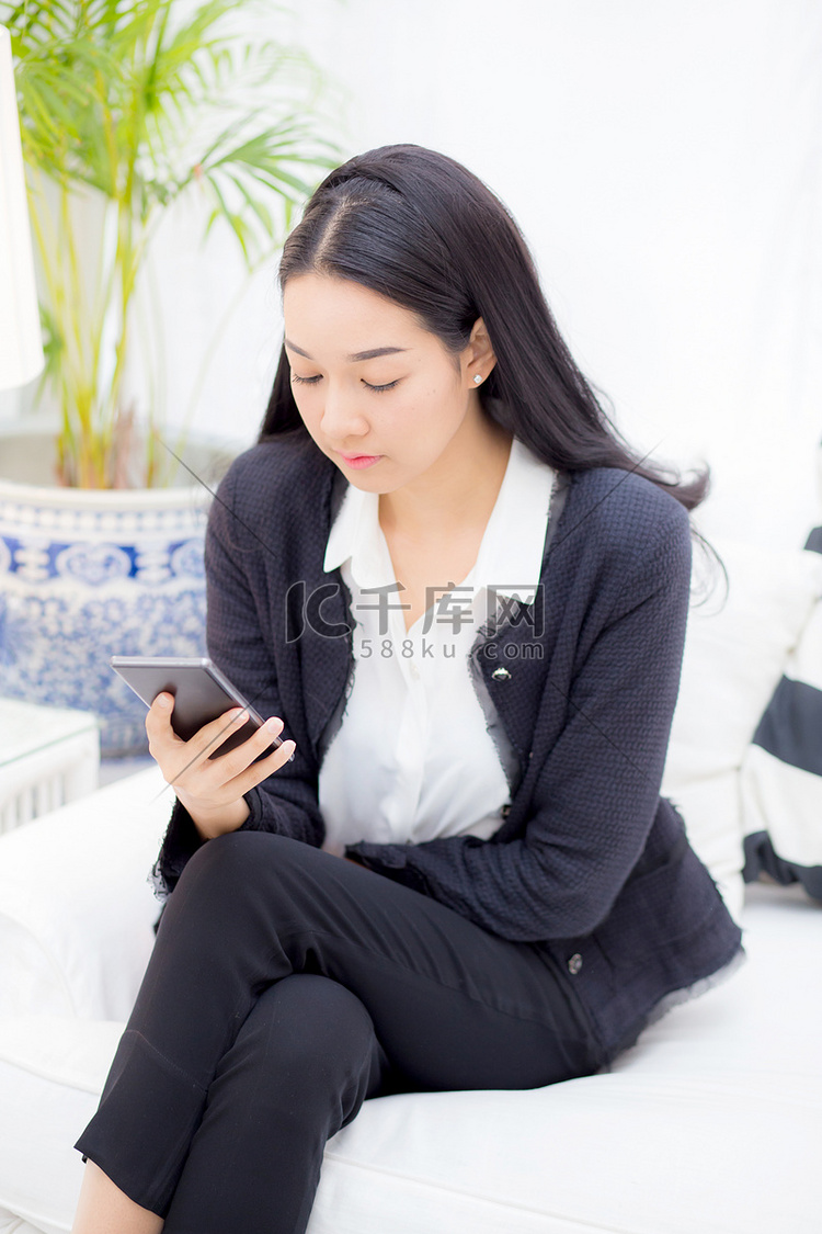 年轻的亚洲女商人坐在桌边看电话，商务高清摄影大图-千库网