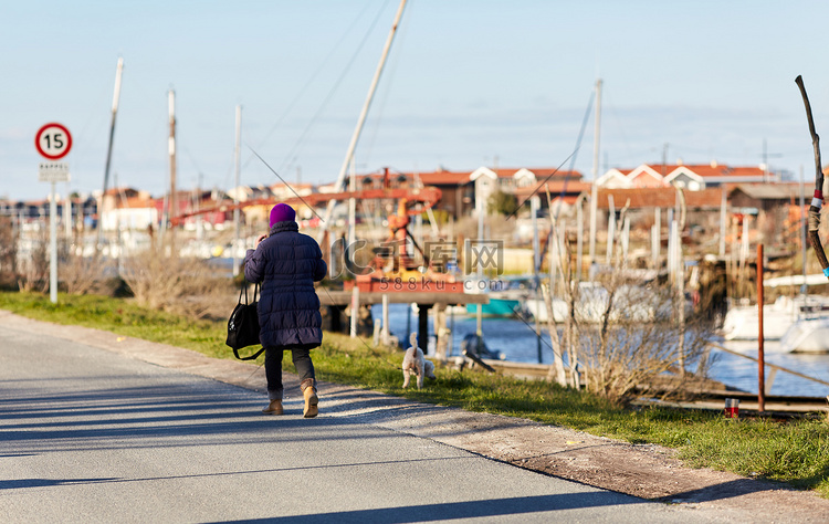 带着贵宾犬走在路上的女人高清摄影大图-千库网