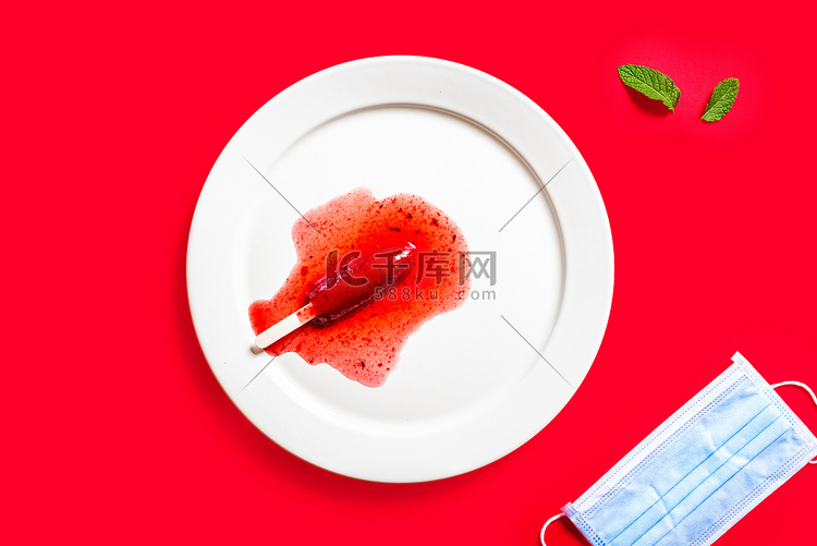 白色圆盘上美味的解冻草莓冰棒和红色背景上的医用面具高清摄影大图-千库网