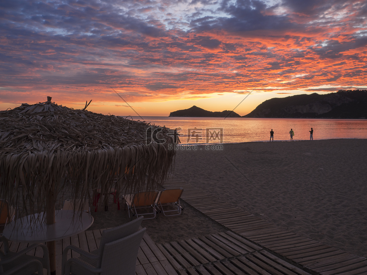 希腊科孚岛的 Agios Georgios Pagon 海滩日落后美丽的蓝色粉红色橙色云彩，太阳伞空荡荡的日光浴床，人们欣赏天空，欣赏波尔图蒂莫尼湾的景色高清摄影大图-千库网
