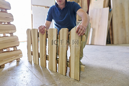 男木匠在木工中展示新制作的木制低围栏高清摄影大图-千库网