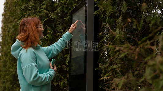 一名妇女使用街头自助服务终端通过智能手机进行非接触式支付。高清摄影大图-千库网