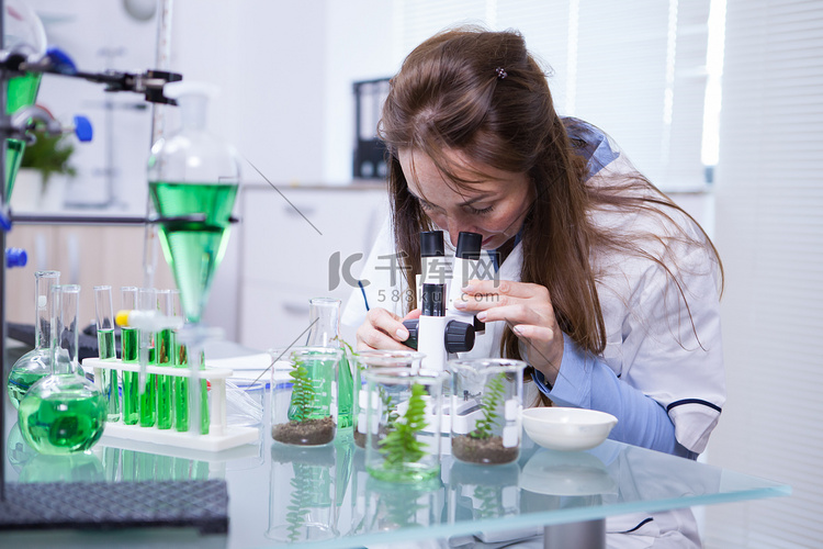 女科学家在生物技术实验室调整她的显微镜高清摄影大图-千库网