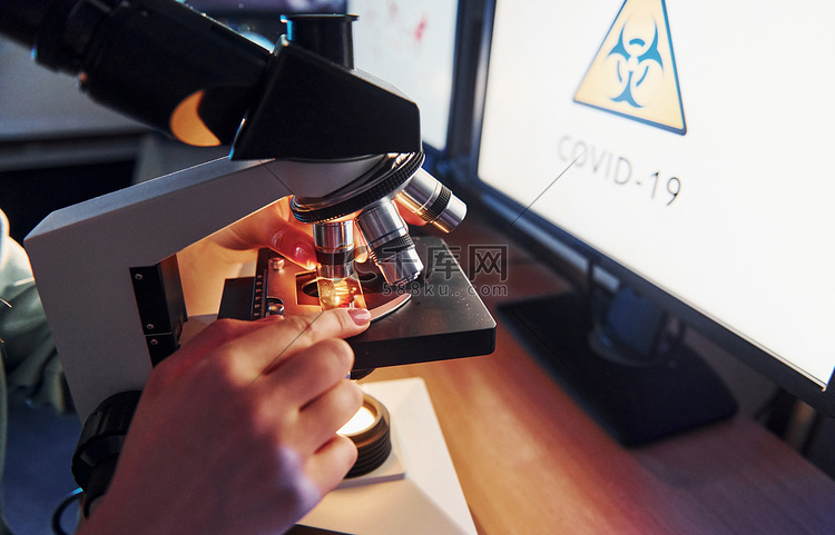 在实验室用显微镜工作的人的手的特写视图。高清摄影大图-千库网