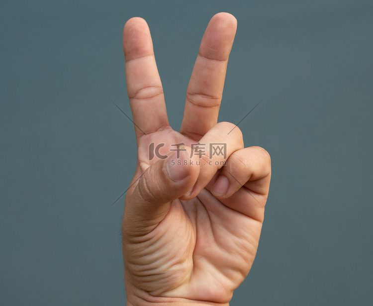 两个手指在蓝色背景上举起。高清摄影大图-千库网