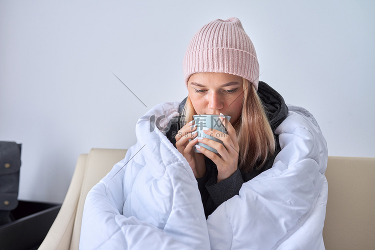 寒冷的秋冬季节，坐在温暖毯子下的沙发上的少女高清摄影大图-千库网