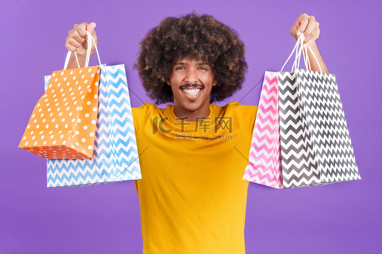 非洲男子在展示购物袋时对着镜头微笑高清摄影大图-千库网