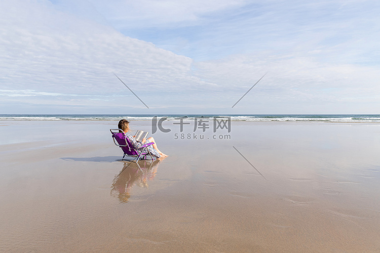 坐在沙滩椅上看书的女人高清摄影大图-千库网