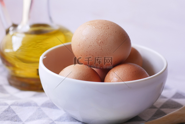 碗里的鸡蛋和桌上的橄榄油的特写高清摄影大图-千库网