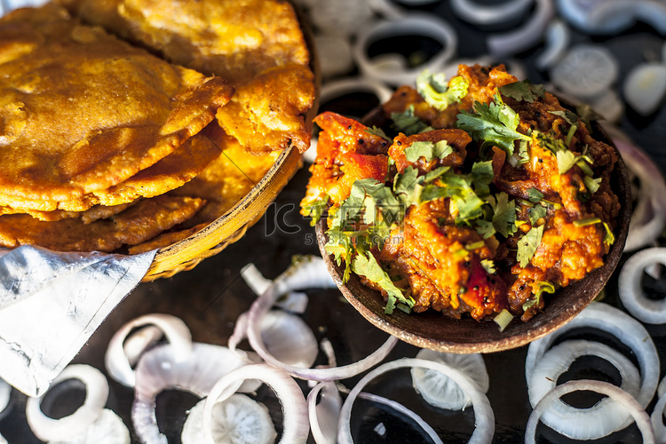 Batate ki sukhi bhaji 或土豆 sabji 在粘土碗中的特写镜头，以及一些干燥的普通油炸 puri 和一些黑色表面上的切 ...