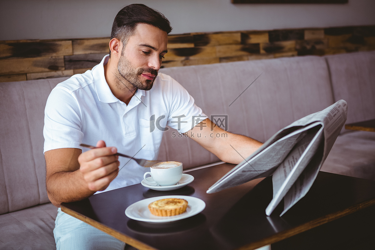 年轻人喝杯咖啡看报纸高清摄影大图-千库网