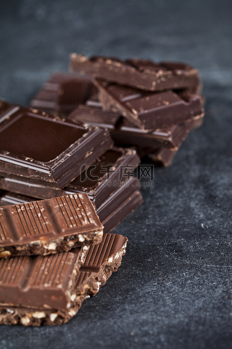 大块的碎巧克力堆放在黑板上。高清摄影大图-千库网