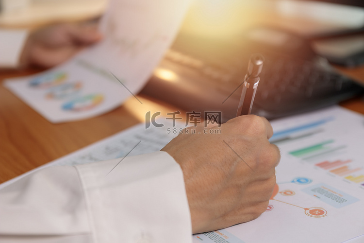 关闭商业女性的手在纸上使用笔写图表。高清摄影大图-千库网