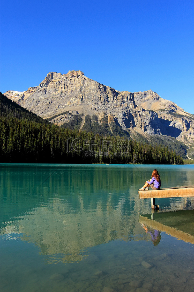 年轻女子坐在 Yoho 国家公园翡翠湖的码头上高清摄影大图-千库网