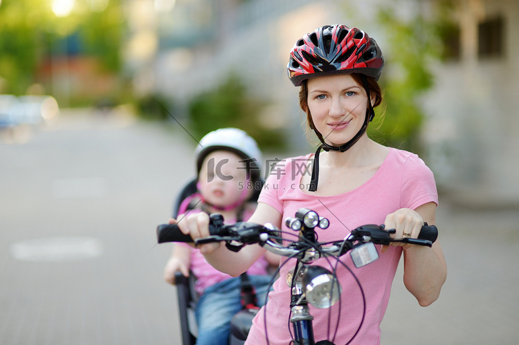 骑自行车的年轻母亲和她蹒跚学步的女孩高清摄影大图-千库网