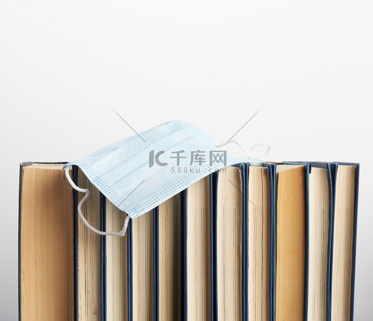 白色 b 上堆放着各种书籍和一次性医用口罩高清摄影大图-千库网