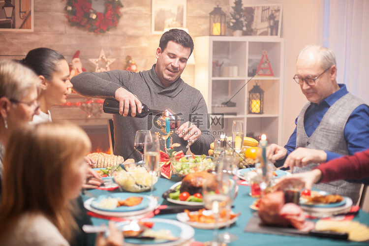 快乐的丈夫往玻璃杯里倒红酒高清摄影大图-千库网