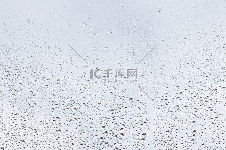 灰色天空背景下的雨滴落在窗户玻璃表面上。高清摄影大图-千库网