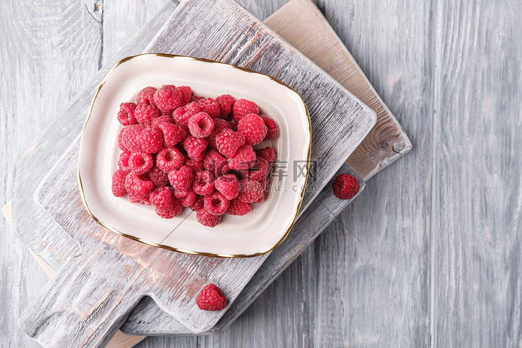 旧切板上盘子里的覆盆子水果高清摄影大图-千库网