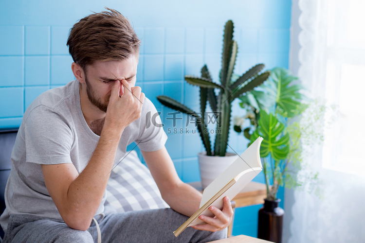 年轻人在客厅的沙发上看书。高清摄影大图-千库网