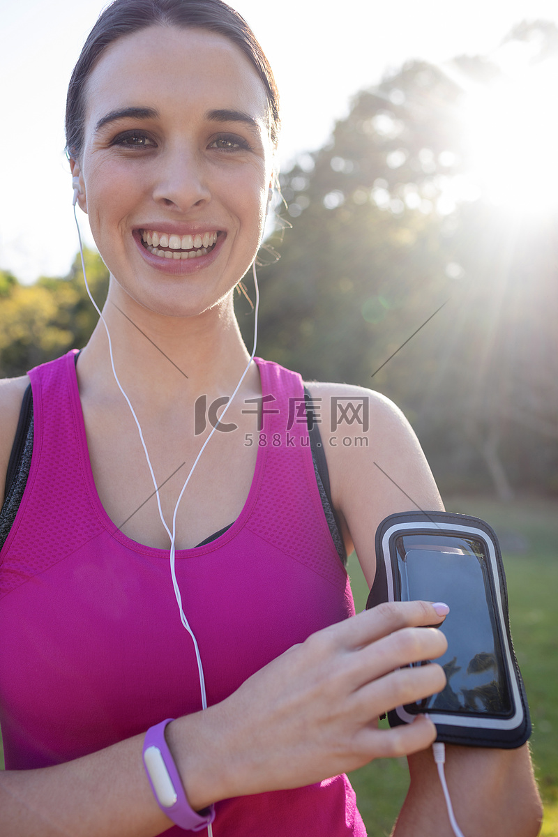 微笑的女性慢跑者在手机上听音乐高清摄影大图 千库网