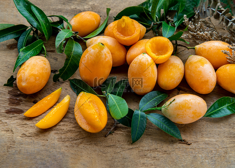 新鲜的玛丽安李子甜黄色或 mayong-chit 与木制背景上的绿叶。高清摄影大图-千库网