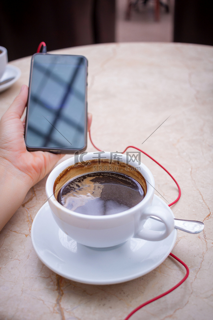 手边的智能手机和桌上白色杯子里的咖啡高清摄影大图-千库网