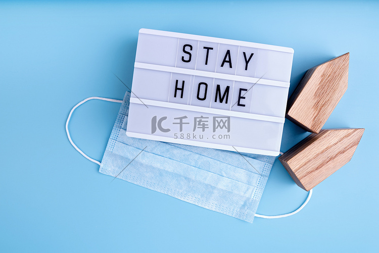 Please Stay Home 字样位于灯箱上，灯箱上有木屋，粉红色背景上有面具顶视图高清摄影大图-千库网