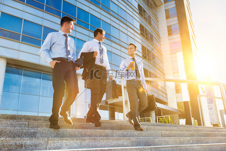 成熟的商人下班后走下楼对着办公楼聊天高清摄影大图-千库网