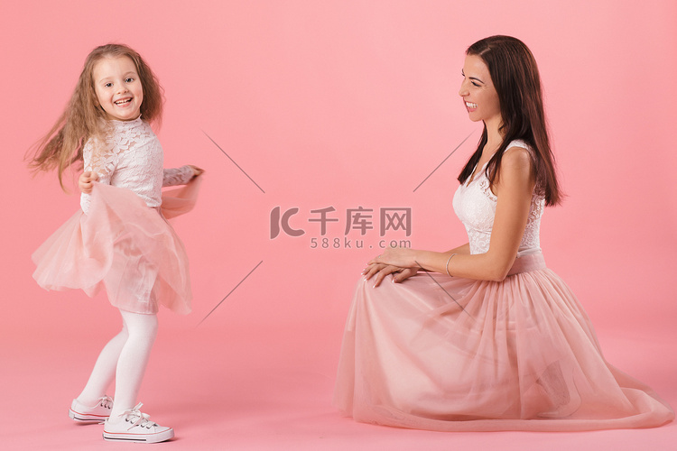 粉红色背景中迷人的母亲和微笑的女儿高清摄影大图-千库网