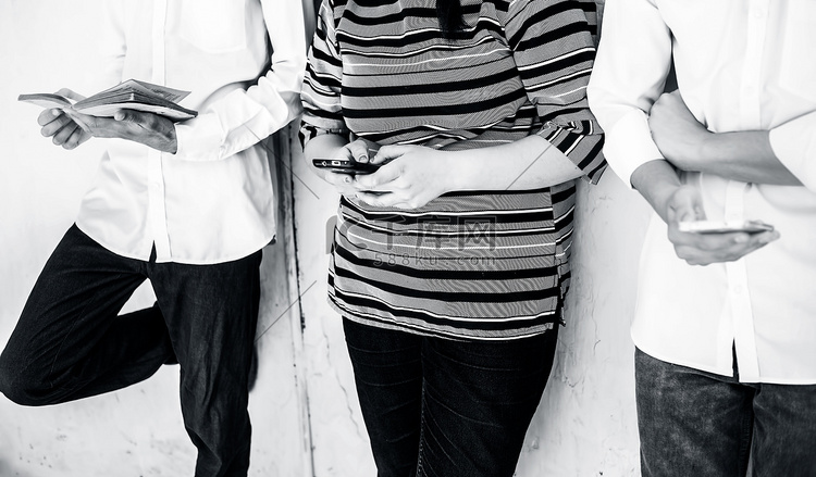 多民族朋友站在墙边，在社交媒体上冲浪。高清摄影大图-千库网