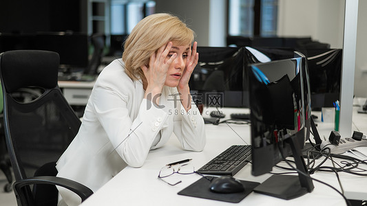 疲惫的白人妇女坐在办公室的办公桌前。高清摄影大图-千库网