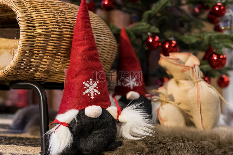 圣诞精灵坐在圣诞树附近。冬季和新年的装饰布置，圣诞老人木偶。斯堪的纳维亚侏儒戴着长胡子的红帽，圣诞装饰玩具高清摄影大图-千库网