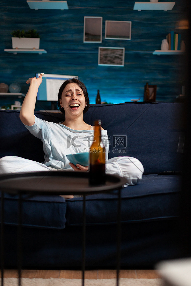 有兴趣的女人吃爆米花，看电视上有趣的连续剧。高清摄影大图-千库网