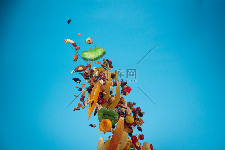 干果和蜜饯水果和坚果在蓝色背景上飞行。高清摄影大图-千库网
