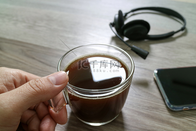 手持咖啡杯或茶和 voip 耳机，w 上的智能手机高清摄影大图-千库网