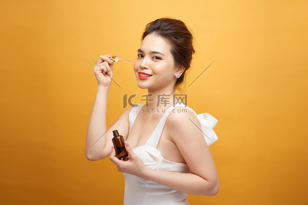 用吸管在年轻女子脸上涂抹化妆油的特写镜头。高清摄影大图 千库网