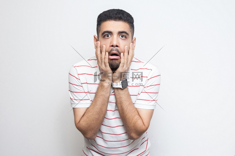 年轻人双手放在脸上站着，用令人难以置信的表情看着相机。高清摄影大图-千库网