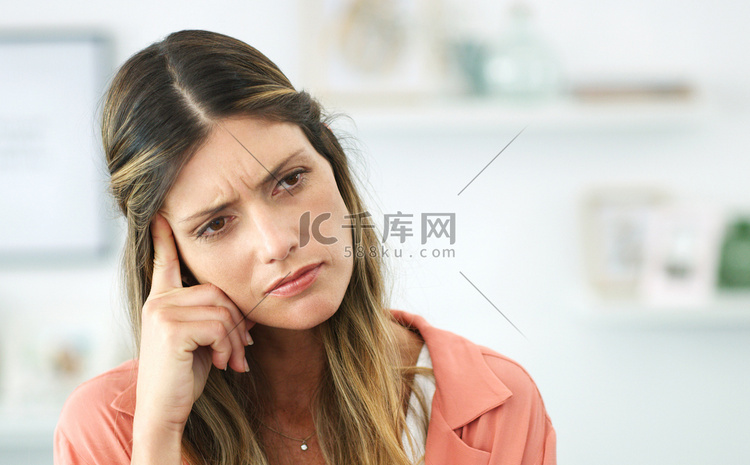 我感到非常困惑……一个年轻女子坐在家里看起来很沮丧。高清摄影大图-千库网