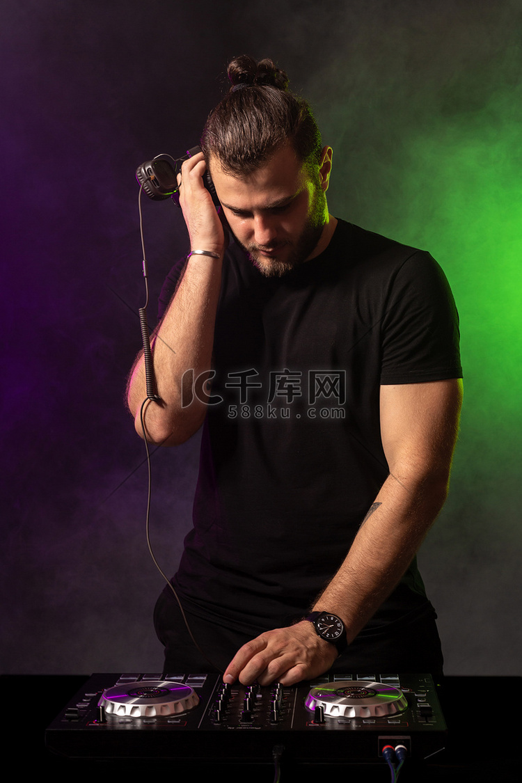 DJ 在色彩缤纷的雾背景下在混音器上演奏音乐高清摄影大图-千库网