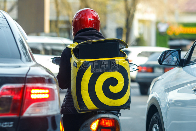 送餐员 Yandex 送餐，背着黄色背包，戴着头盔，骑在一辆轻便摩托车上。高清摄影大图-千库网